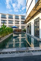 Um hotel moderno com piscina, varandas e área externa coberta.