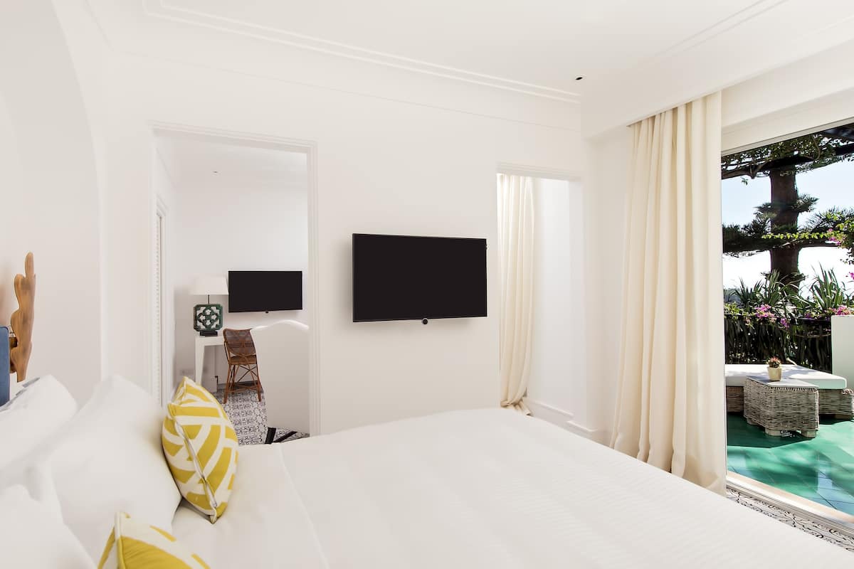 Quarto de hotel com uma cama grande, televisão de tela plana, escrivaninha com cadeira e vista para a piscina e área externa.