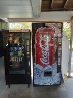 Duas máquinas de venda automática, uma com o logotipo da Coca-Cola e outra com petiscos.