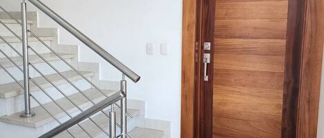 Uma escada com corrimão de metal leva a uma porta de madeira com o número 2 em cima.