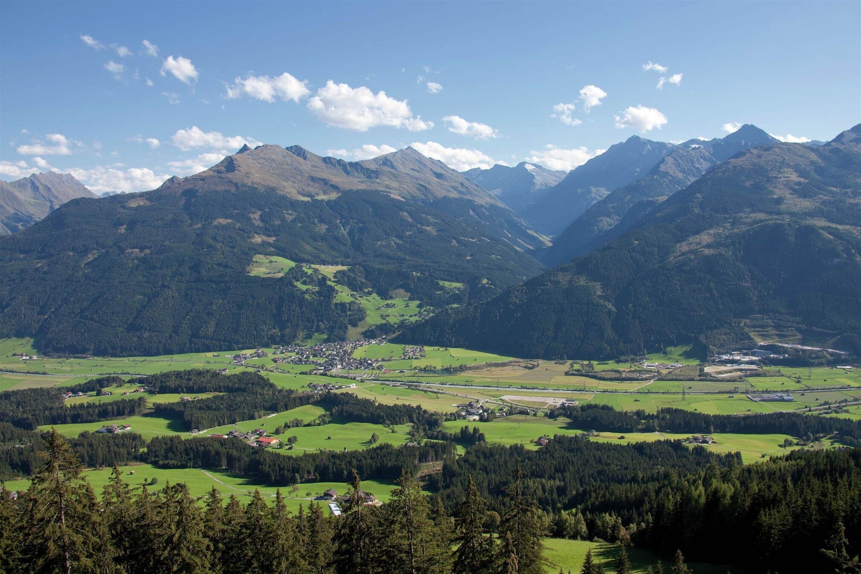 Paisagem montanhosa com um vale, casas e uma pequena cidade.
