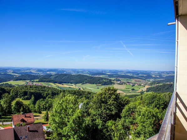 Vista panorâmica de uma varanda com vista para um vale com casas e vegetação.
