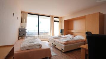 Quarto de hotel com duas camas, uma escrivaninha, uma cadeira, uma televisão e janela com vista para o exterior.