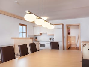Uma cozinha moderna com armários brancos, bancada de madeira e luminária pendente.