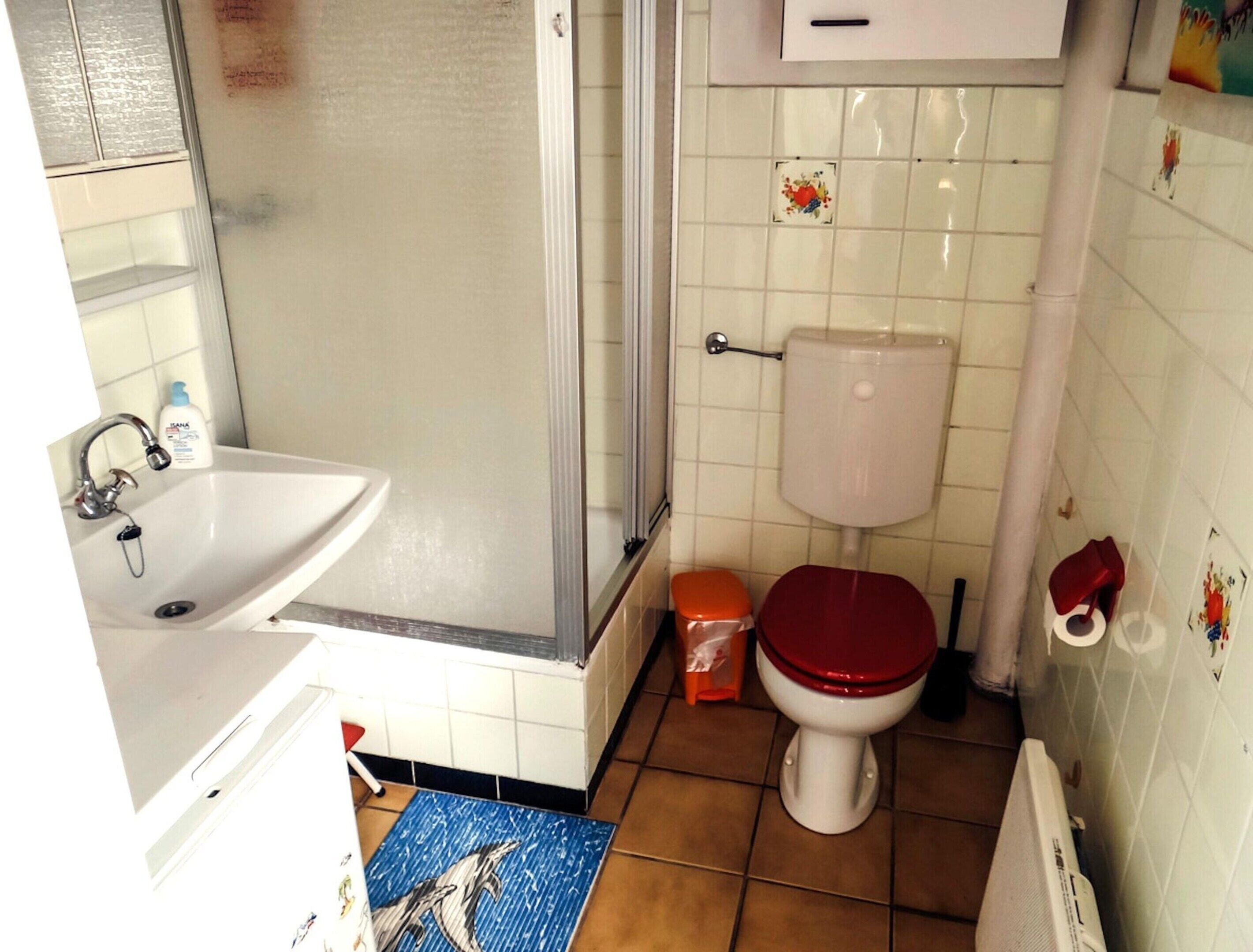 Casa de banho com lavatório branco, sanita e chuveiro.