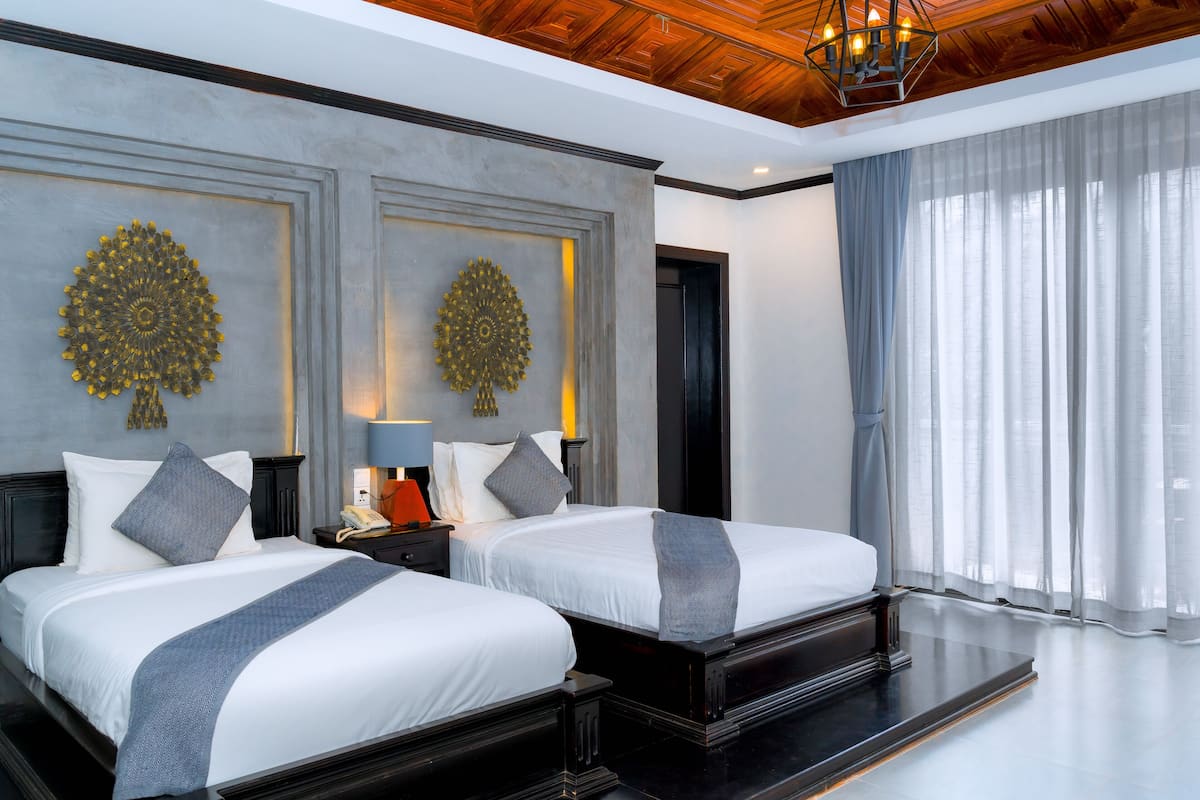 Quarto de hotel moderno com duas camas, teto de madeira e arte decorativa nas paredes.