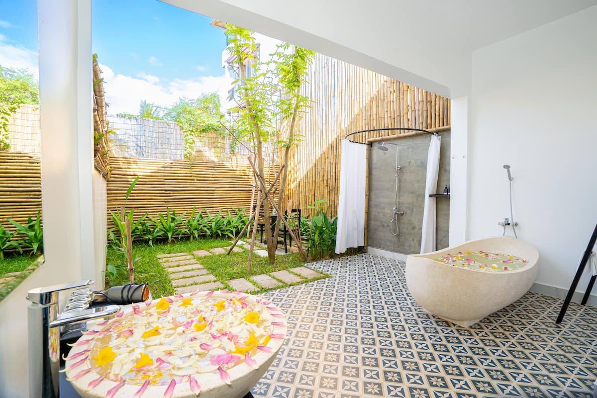 Casa de banho moderna com uma banheira independente, uma pequena pia circular decorada com pétalas de flores e zona de duche.