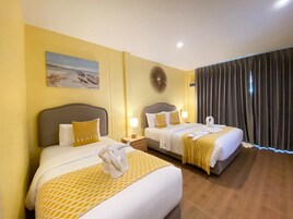 Quarto de hotel com duas camas, um quadro na parede, um espelho redondo e vista para o exterior através das cortinas.