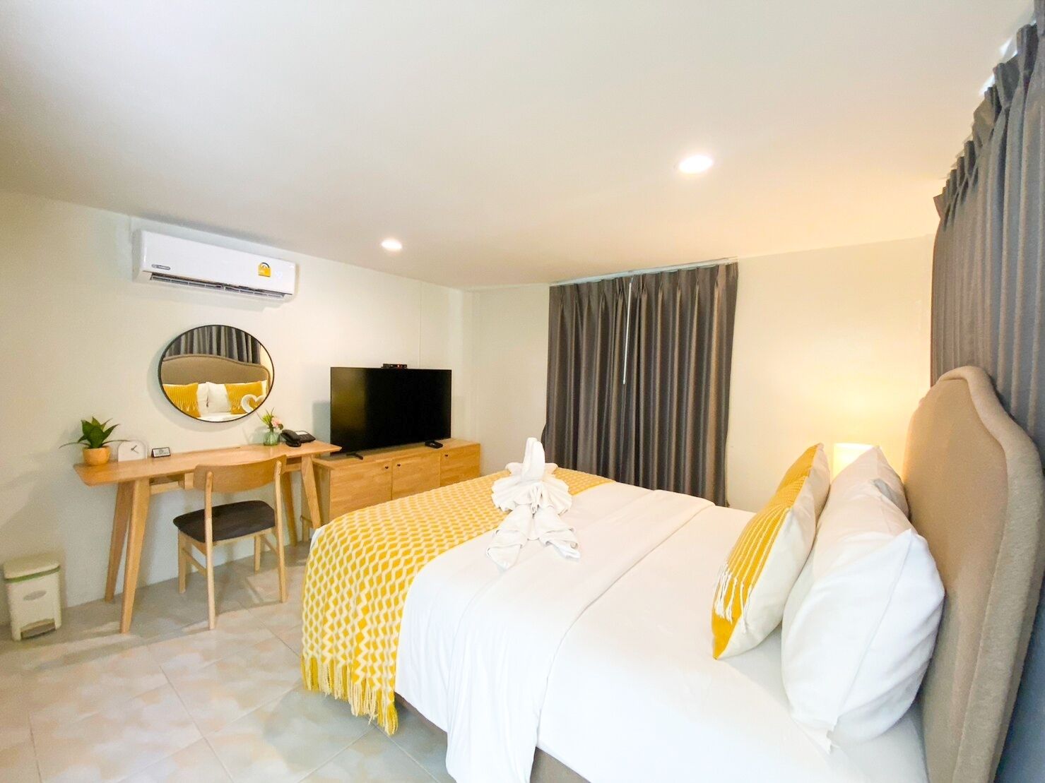 Quarto de hotel com cama, escrivaninha, computador, televisão e ar condicionado.