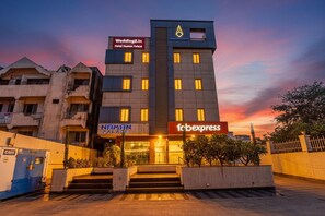 Hotel com fachada moderna, vários andares e entrada imponente com degraus.