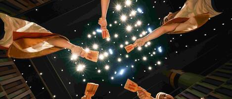 Um grupo de pessoas de mãos dadas formando um círculo, com uma luz intensa acima.
