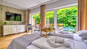 Quarto moderno com uma cama grande, uma escrivaninha e uma televisão.