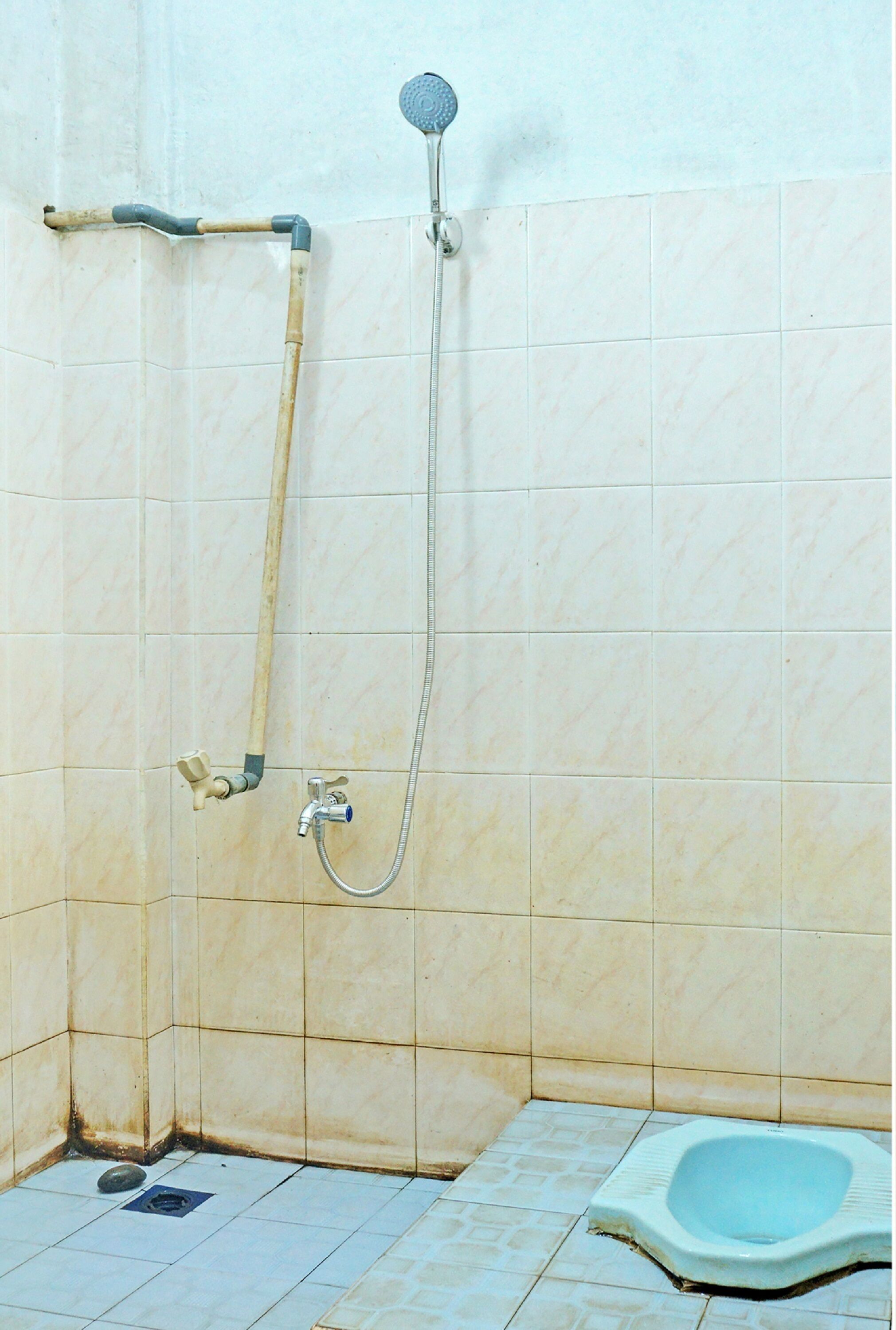 Casa de banho com chuveiro, sanita e ralo.