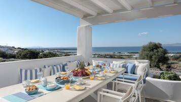 Mesa de jantar posta para o café da manhã, com vista para o mar e a paisagem.