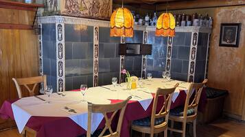 Uma sala de jantar com uma mesa de madeira posta para quatro pessoas, cercada por cadeiras com assentos acolchoados.