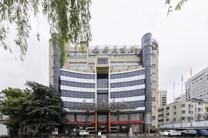 Um edifício com várias andares, fachada curva, grandes janelas e entrada imponente.