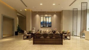 Um lobby moderno com área de estar central, uma grande obra de arte emoldurada na parede e um alto painel decorativo.