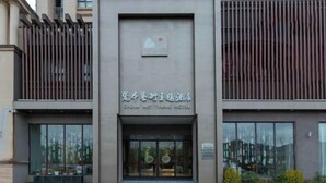 Exterior do Hotel China Art Theme, com fachada moderna, grandes janelas de vidro e placa indicando o nome do hotel.