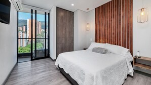 Quarto moderno com uma cama grande, porta de correr de vidro para uma varanda e vista para a cidade.