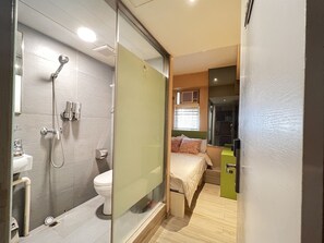 Uma casa de banho moderna com chuveiro, sanita e lavatório.