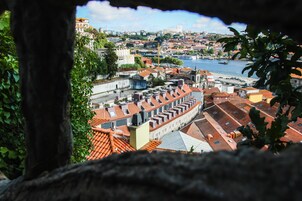 Paisagem urbana histórica com uma torre redonda imponente, edifícios com telhados de terracota e um rio.