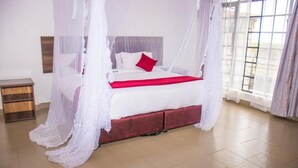 Uma cama com dossel, um travesseiro vermelho e uma mesinha de cabeceira de madeira.