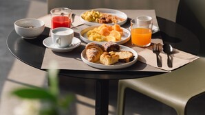 Uma mesa de café da manhã com pratos de comida, uma xícara de café e um copo de suco de laranja.