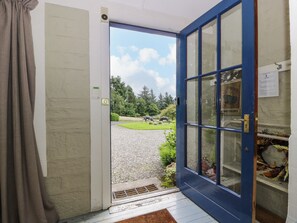 Uma porta azul com vista para um caminho de cascalho e vegetação.