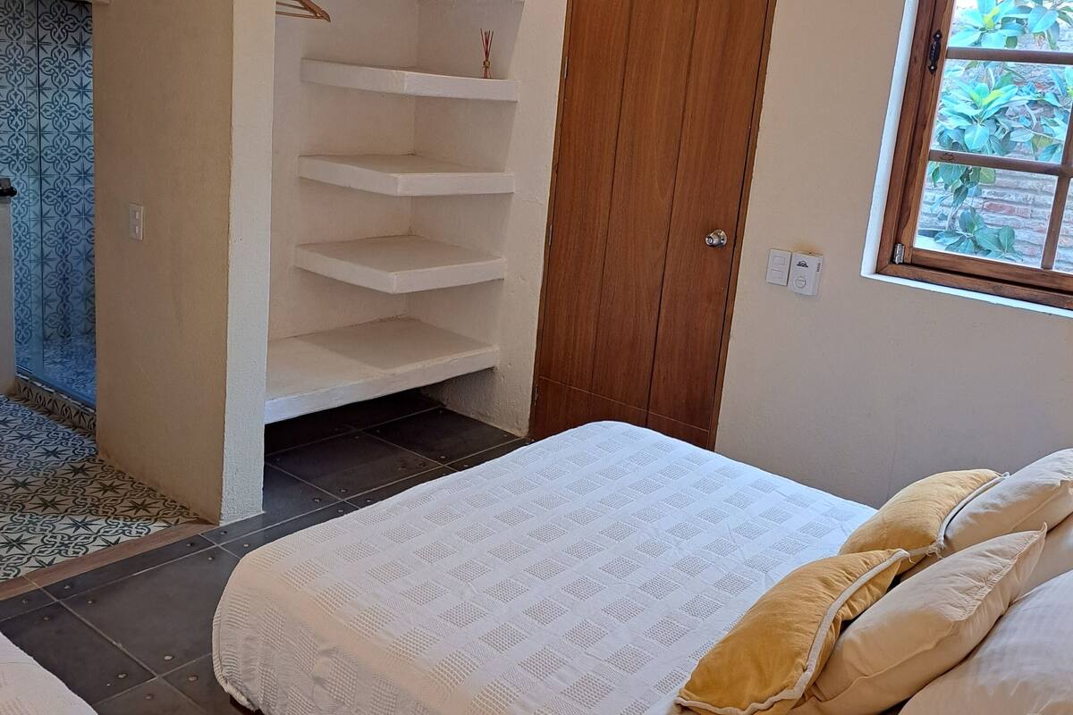Quarto com uma cama, um guarda-roupa e uma janela.