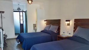 Quarto de hotel com duas camas, televisão e ventoinha no teto.