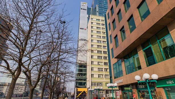 Um edifício de vários andares com design arquitetônico moderno, destacando uma fachada de vidro e uma série de janelas.