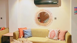 Uma sala de estar com sofá, mesa de centro e ar-condicionado fixado na parede.