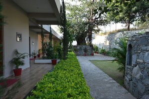 Um caminho bordeado por vasos de plantas, uma parede de pedra e um edifício com design moderno.