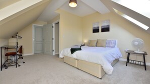 Quarto com cama, mesa de cabeceira e um ventilador.