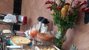Mesa de buffet com diversos alimentos e uma planta decorativa.