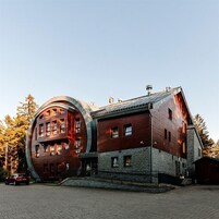 Um edifício com fachada curva singular, várias janelas e base de pedra.