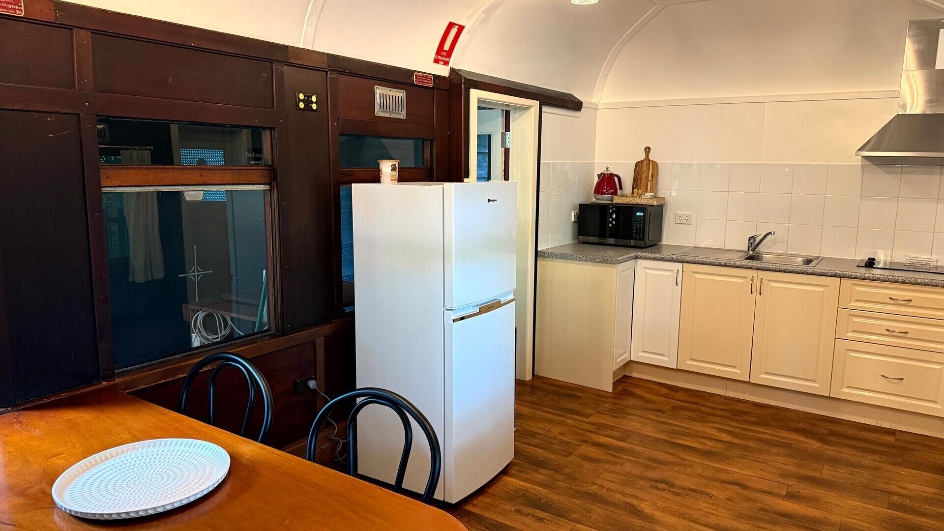 Uma cozinha compacta com geladeira, micro-ondas e pia.