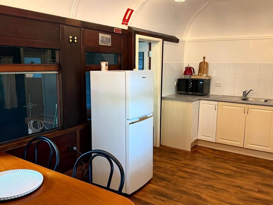 Uma cozinha compacta com geladeira, micro-ondas e pia.