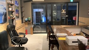 Uma sala de conferências com uma longa mesa de madeira, várias cadeiras, um sofá de couro preto e uma bicicleta ao fundo.