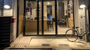 Exterior da Golden Guest House-Hakata, com fachada moderna, entrada destacada, uma bicicleta estacionada e uma placa com o nome do estabelecimento.