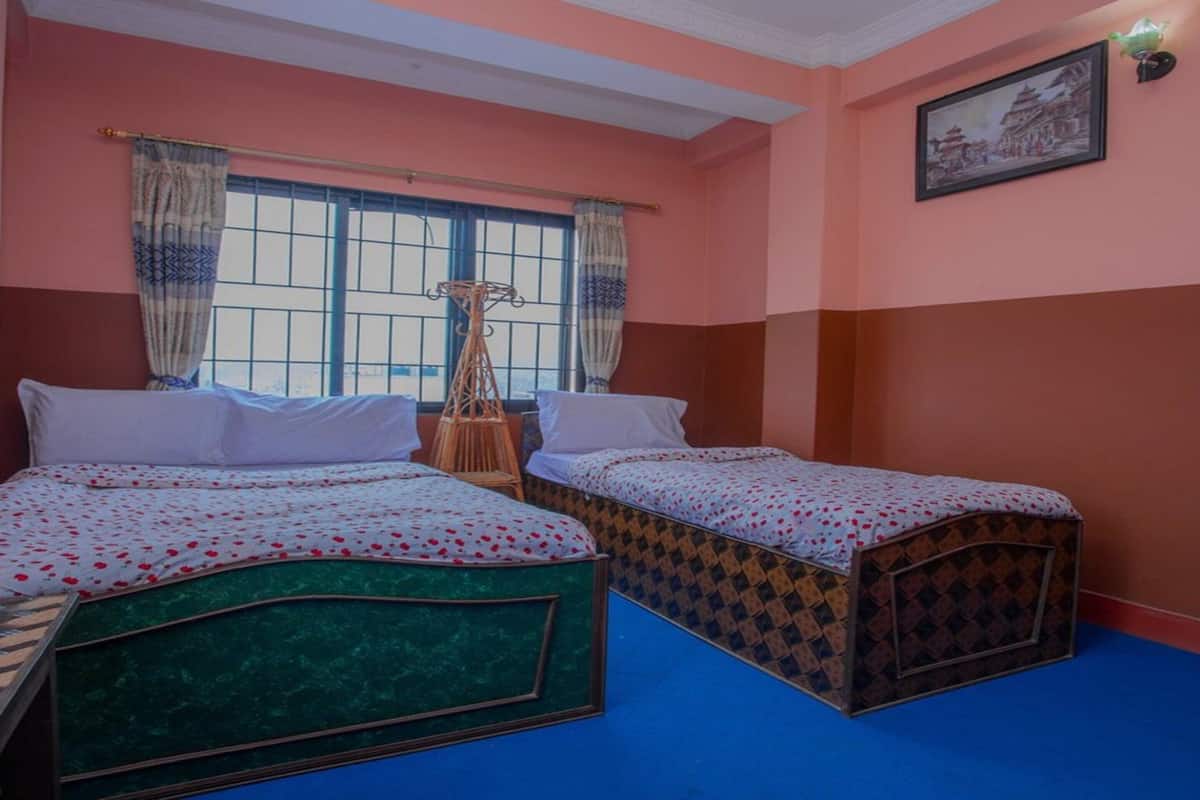 Quarto com duas camas, janela com cortinas, quadro emoldurado na parede e carpete azul.