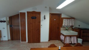 Quarto com portas de madeira, área de cozinha com pia e armários, e mesa de jantar com cadeiras.