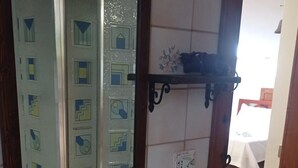 Casa de banho com lavatório branco, espelho em cima e prateleira com produtos de higiene pessoal.