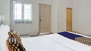 Quarto de hotel com cama, janela com cortinas leves, porta e unidade de ar condicionado.