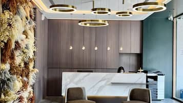 Interior moderno com balcão de recepção, área de estar e detalhe decorativo na parede.