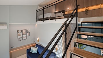 Uma sala de estar moderna com um sofá azul, uma mesa de centro e uma escada com corrimão preto.