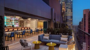 Um bar no terraço com assentos e área de bar, com vista para a cidade.