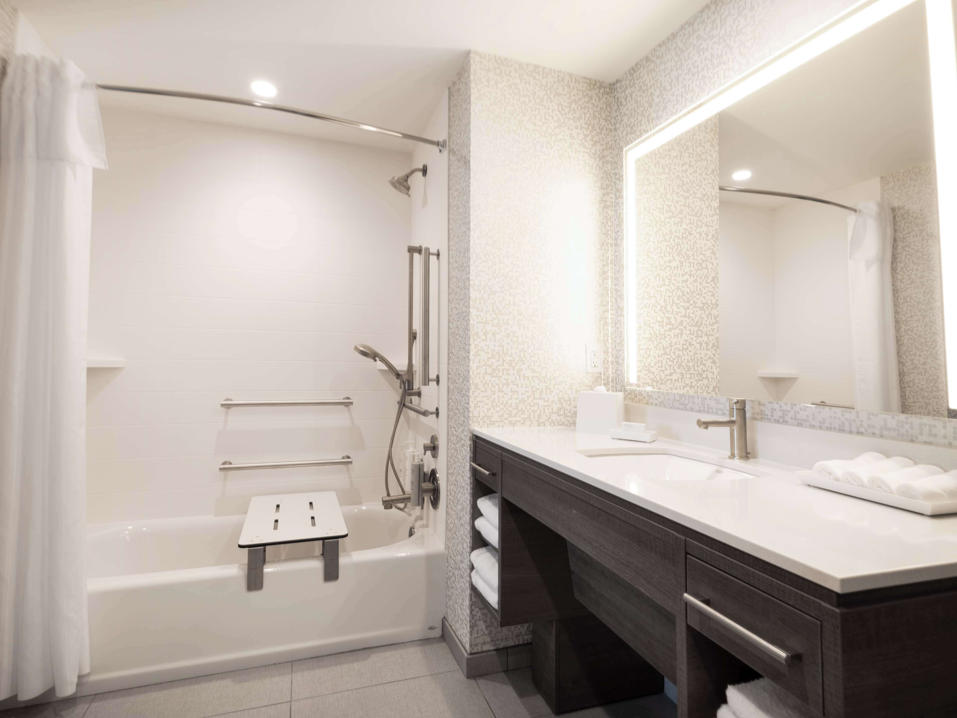 Uma casa de banho moderna com banheira, toucador com espelho e zona de duche.
