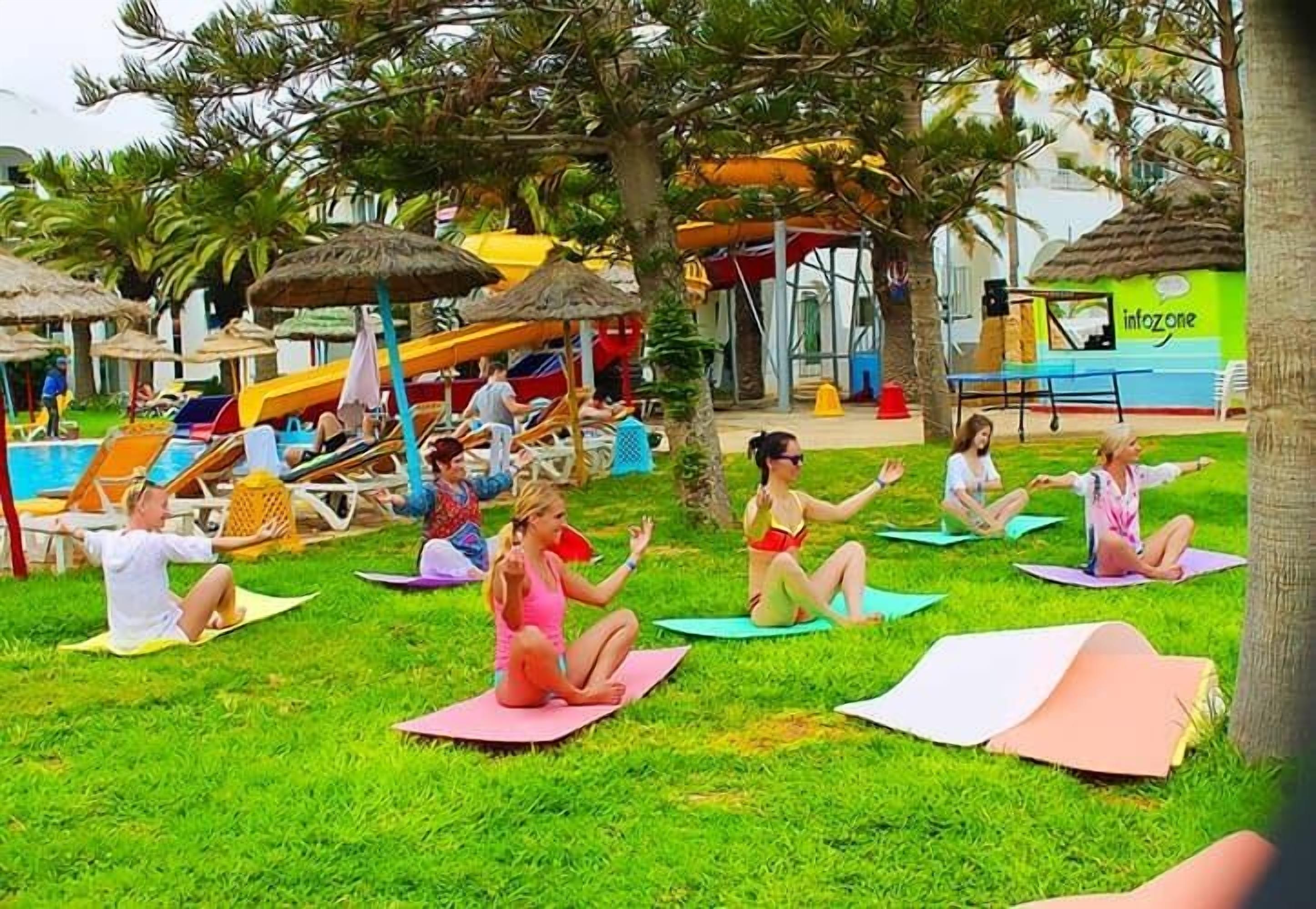 Um grupo de pessoas praticando yoga ao ar livre em tapetes de grama.