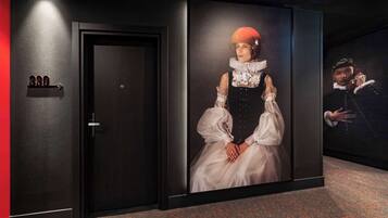 Um corredor com uma porta escura identificada com o número "330" e um retrato grande emoldurado de uma pessoa com vestes históricas.